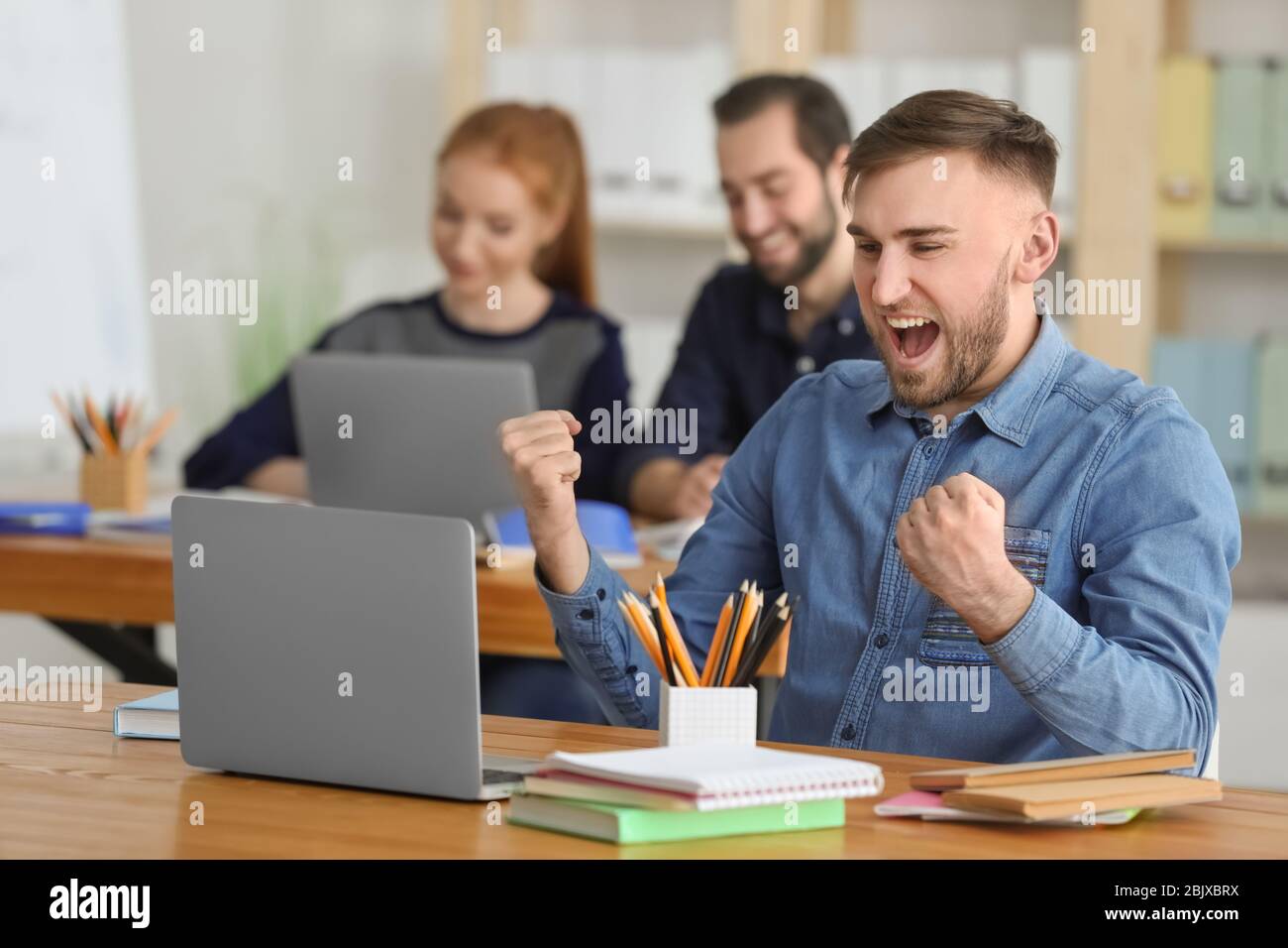 Male student with laptop doing homework in classroom Stock Photo - Alamy