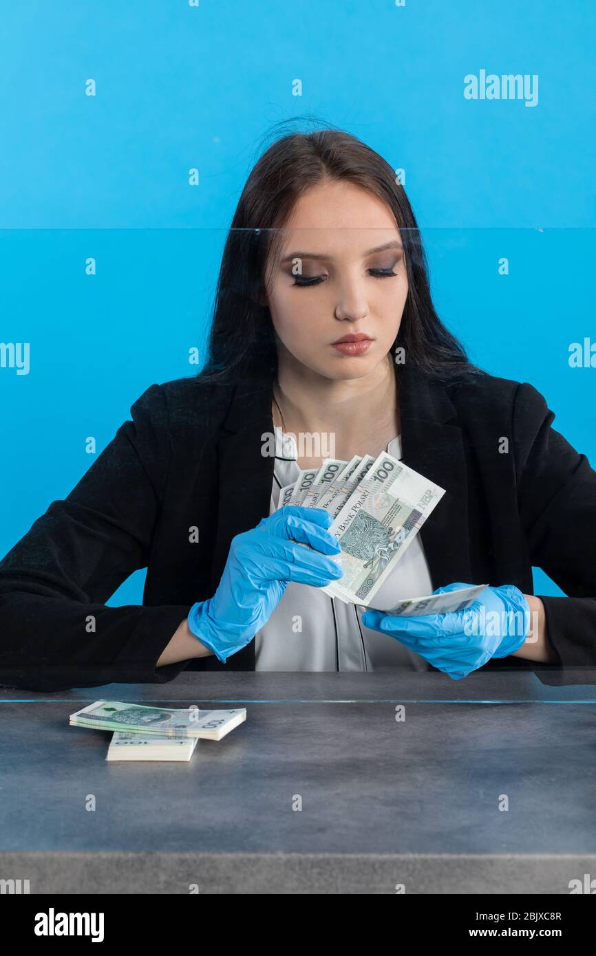 Hand counting banknotes by a young woman at the cashier's window in a ...
