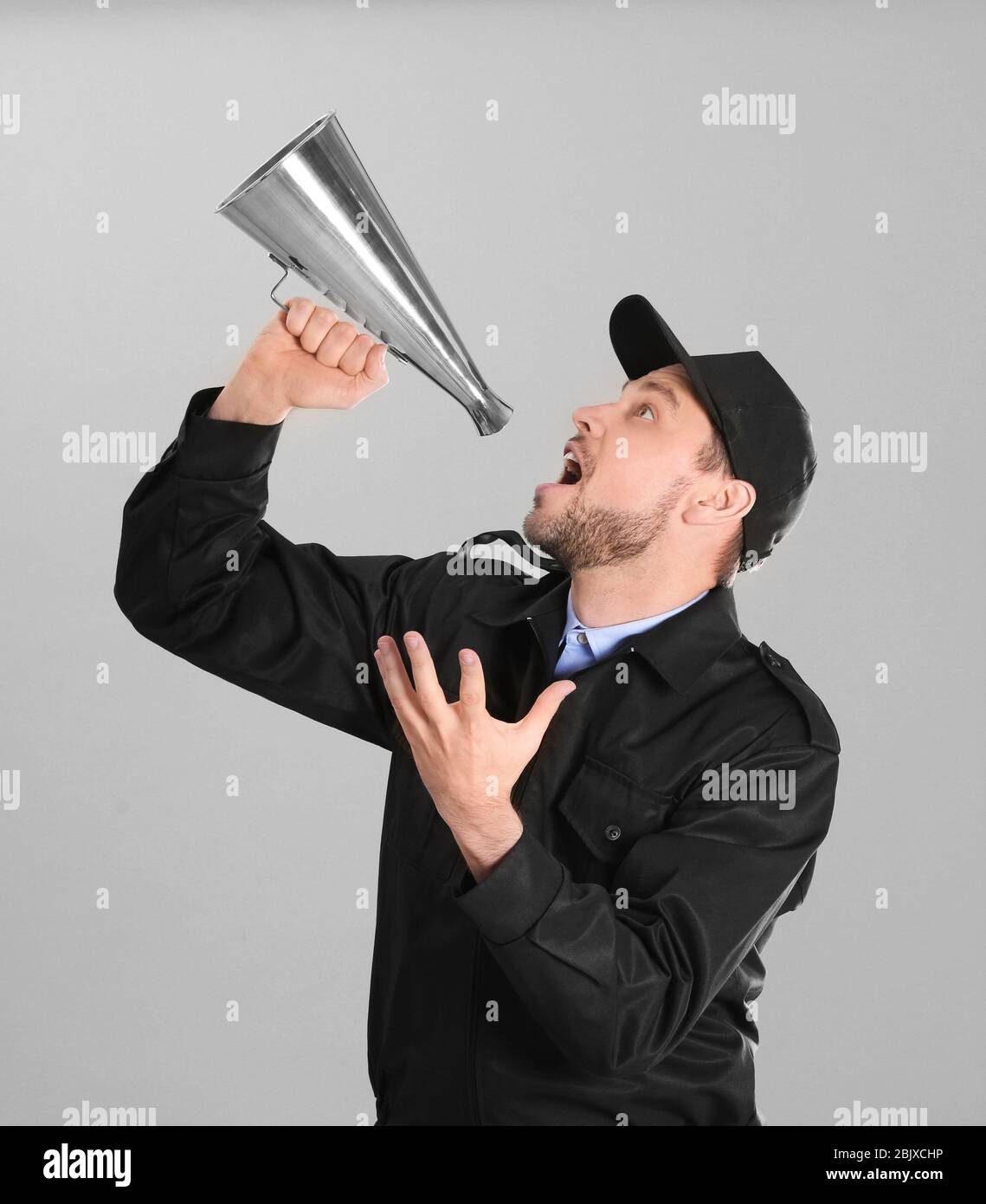 Male security guard with megaphone on grey background Stock Photo - Alamy