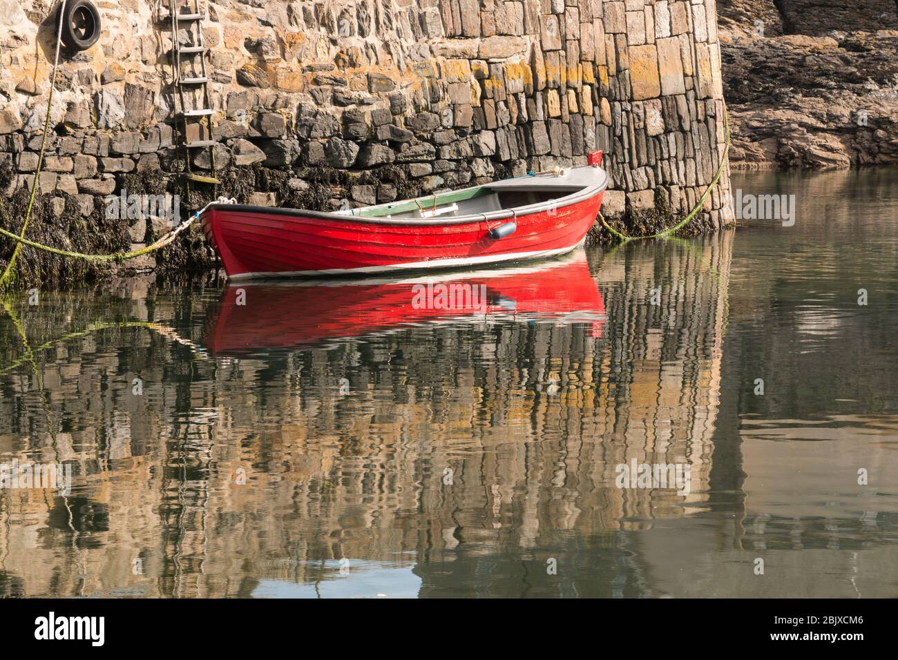 Bright red row boat safely moored in a sea harbour Stock Photo - Alamy