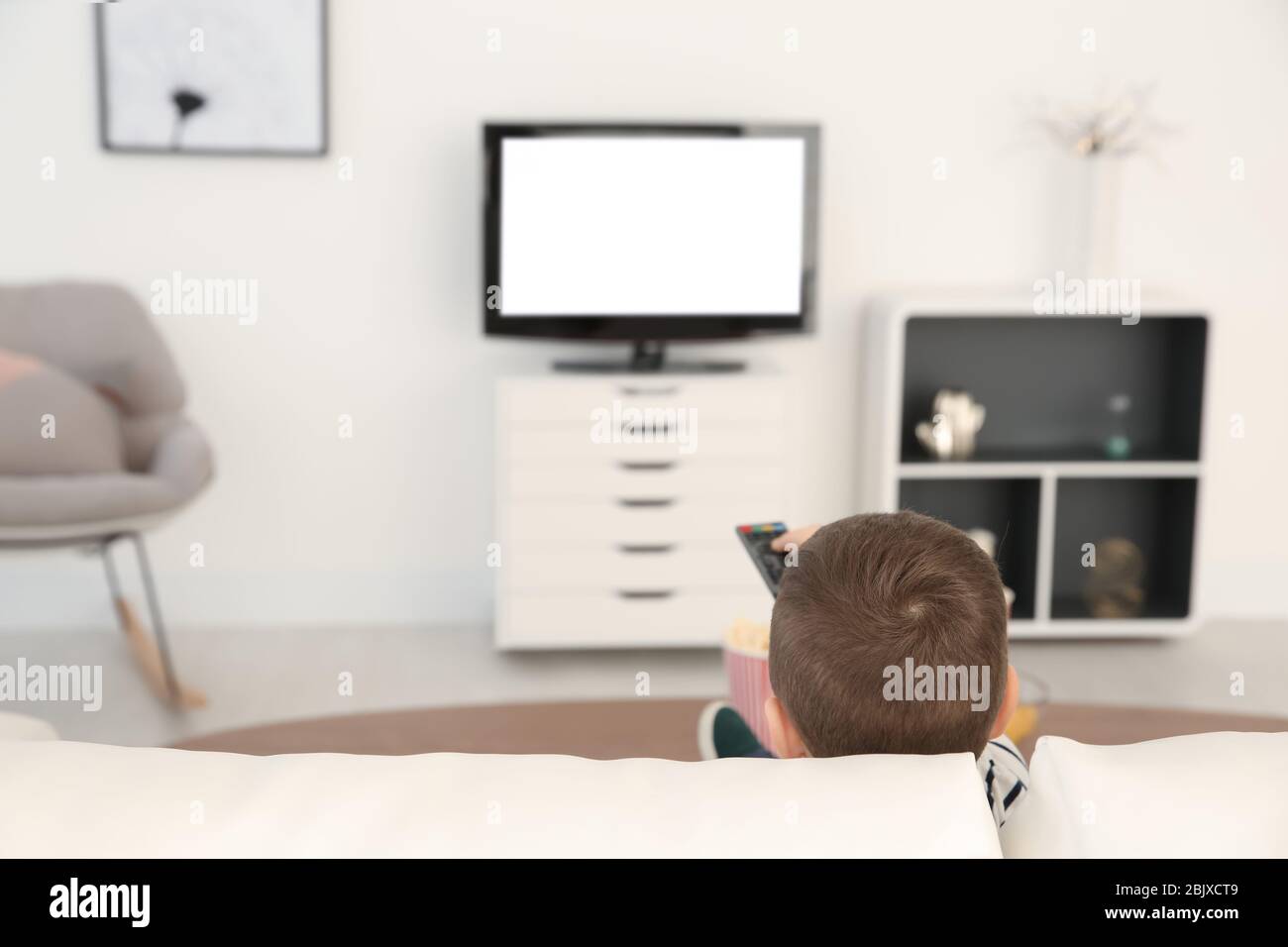Little boy watching TV on sofa at home Stock Photo - Alamy