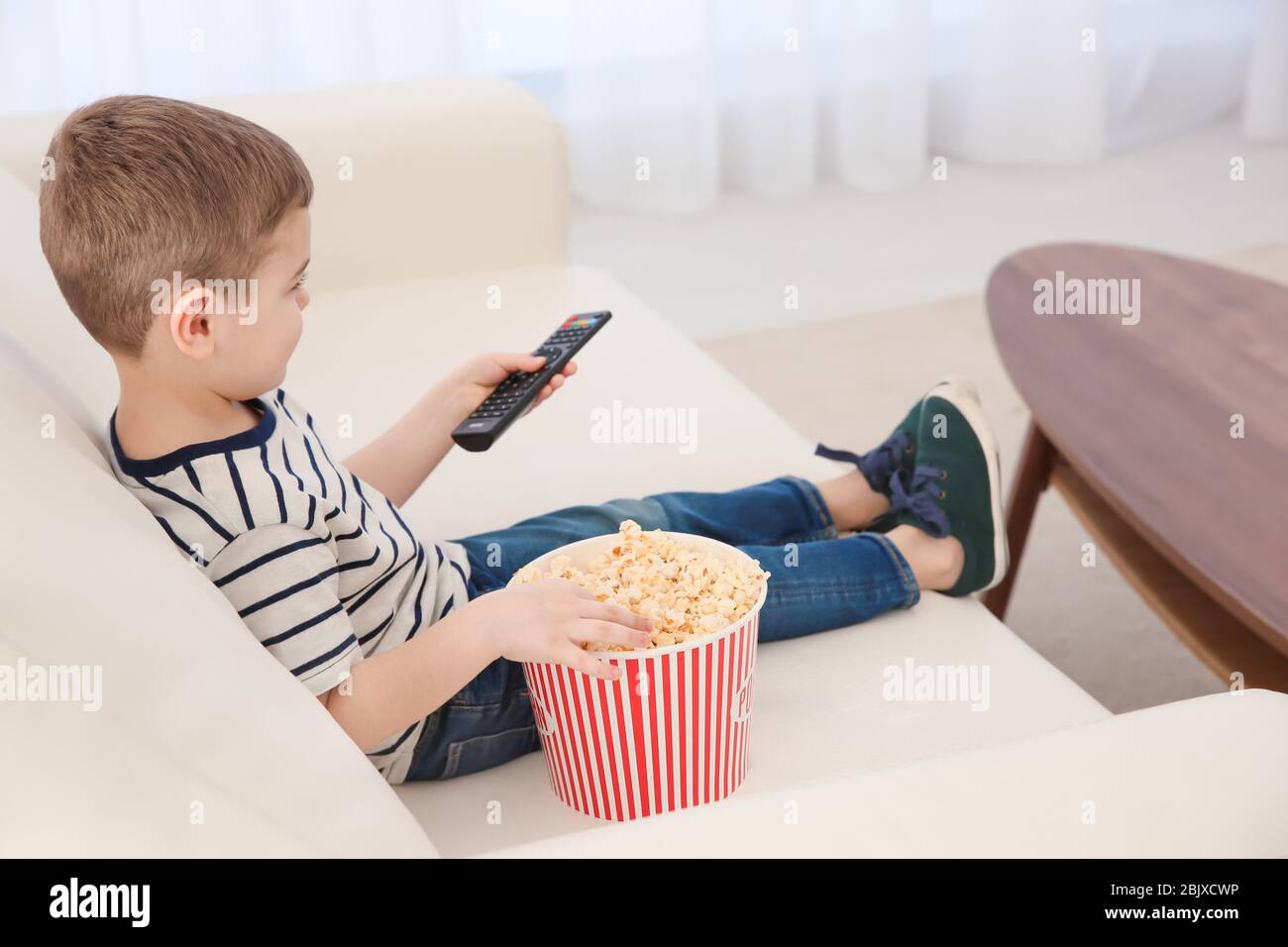 Little boy watching TV on sofa at home Stock Photo - Alamy
