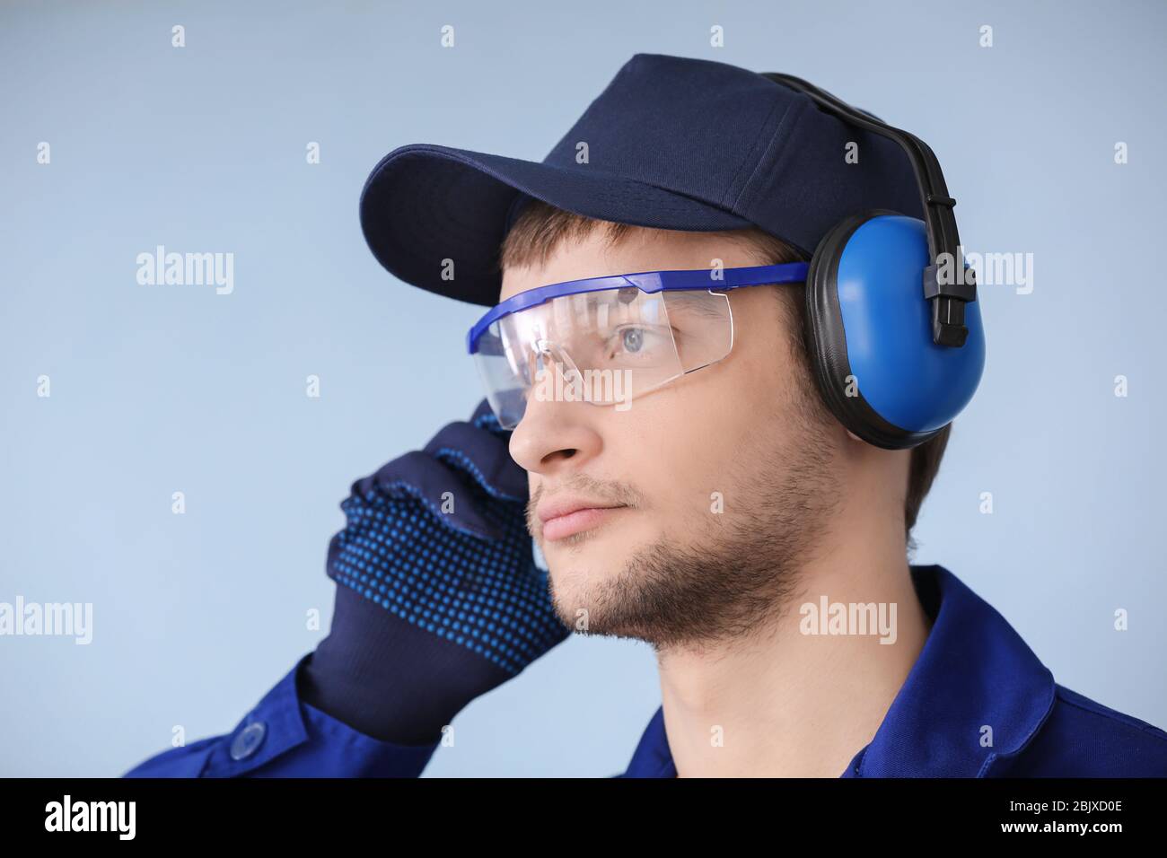 Male worker with headphones on grey background. Hearing protection ...