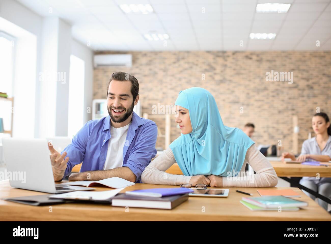Male student and his Muslim classmate using laptop in library Stock ...