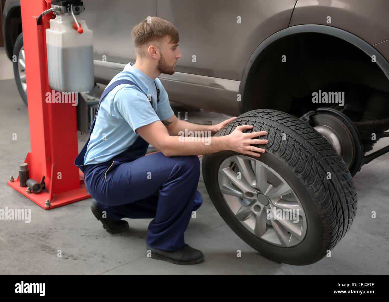 Mechanic changing car wheel in garage. Tire service Stock Photo - Alamy
