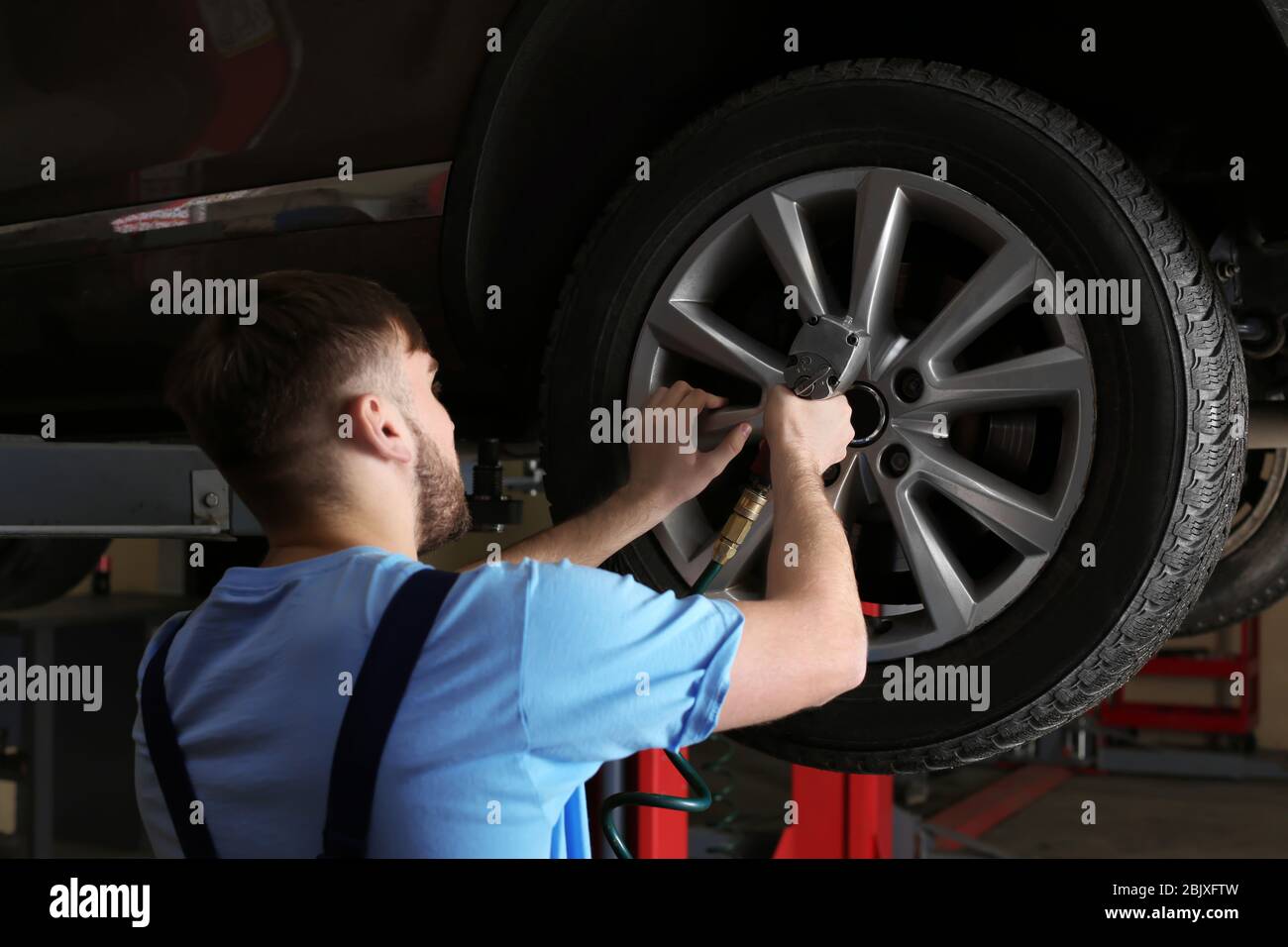 Mechanic changing car wheel in garage. Tire service Stock Photo - Alamy