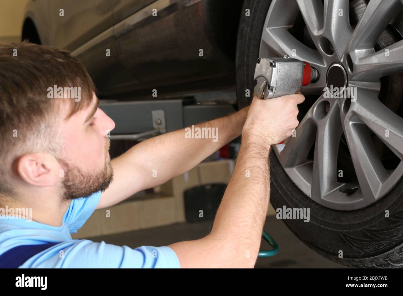 Mechanic changing car wheel in garage. Tire service Stock Photo - Alamy