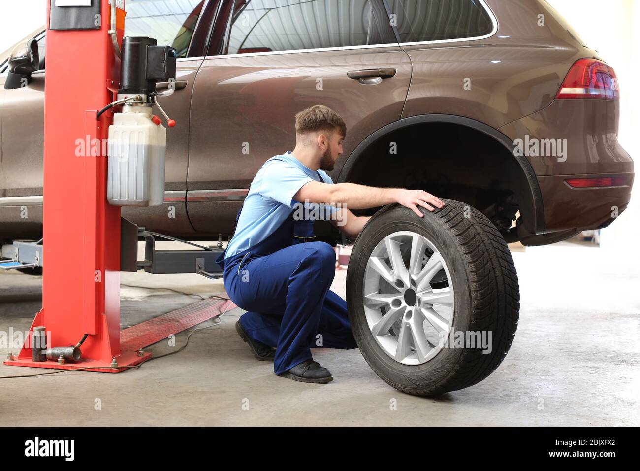 Mechanic changing car wheel in garage. Tire service Stock Photo - Alamy