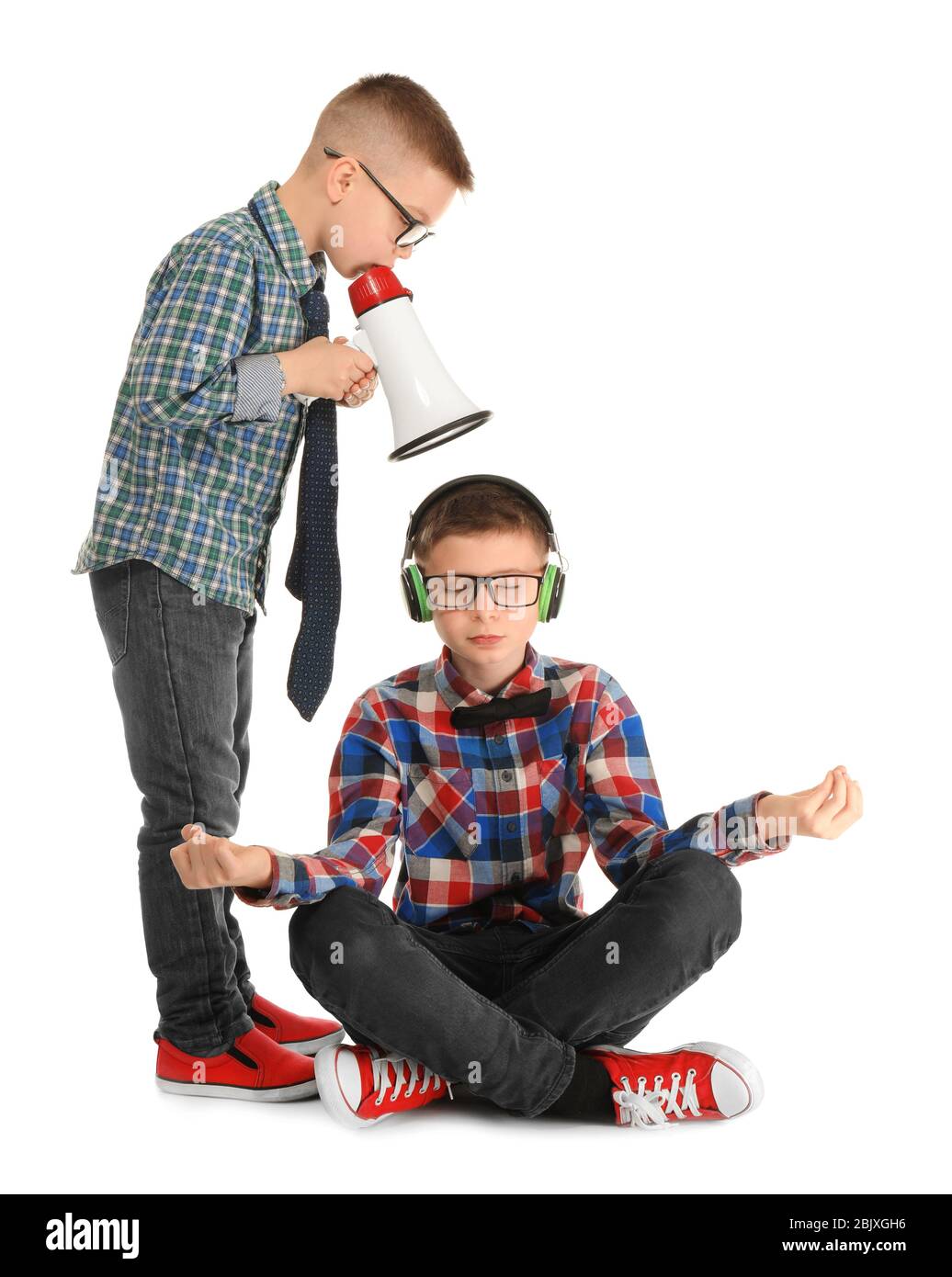 Cute little boy meditating and ignoring his friend with megaphone, on ...