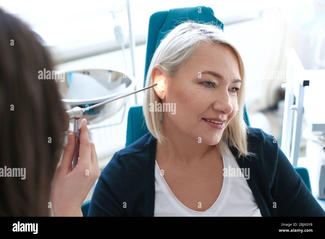 Otolaryngologist examining woman's ear with ENT telescope in hospital ...