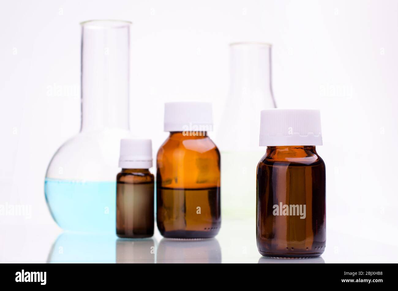 Medicine bottle and laboratory flasks against white background ...