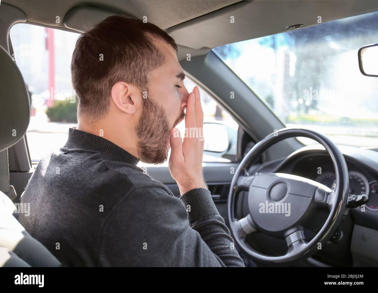 Young man yawning in car during traffic jam Stock Photo - Alamy