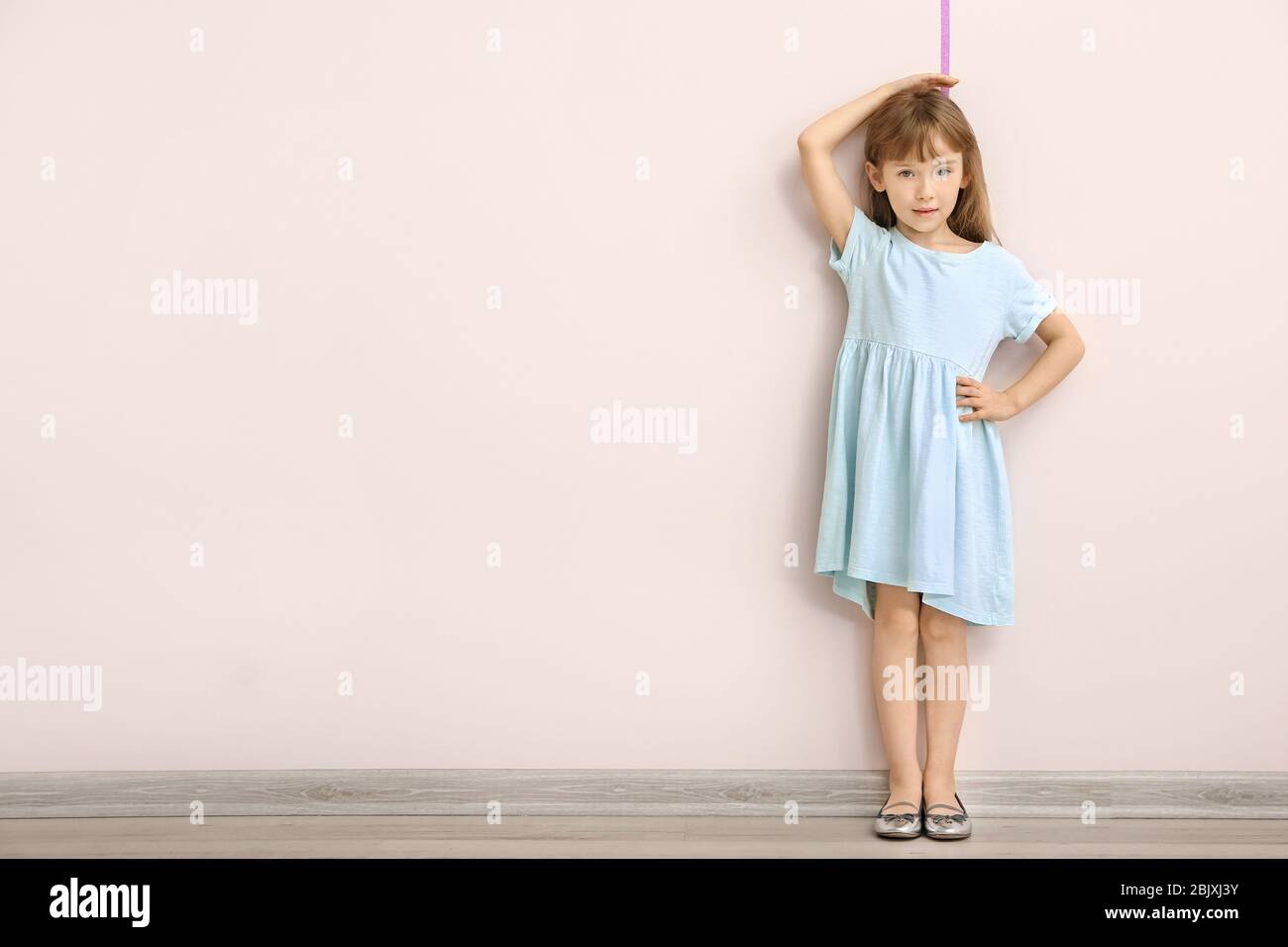 Little girl measuring height near wall Stock Photo - Alamy