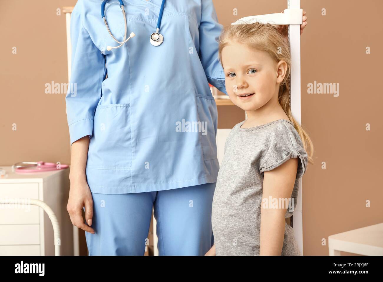 Female nurse measuring height of little girl in hospital Stock Photo ...