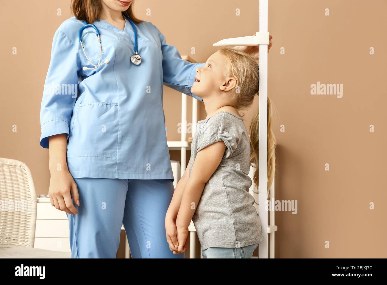 Female nurse measuring height of little girl in hospital Stock Photo ...