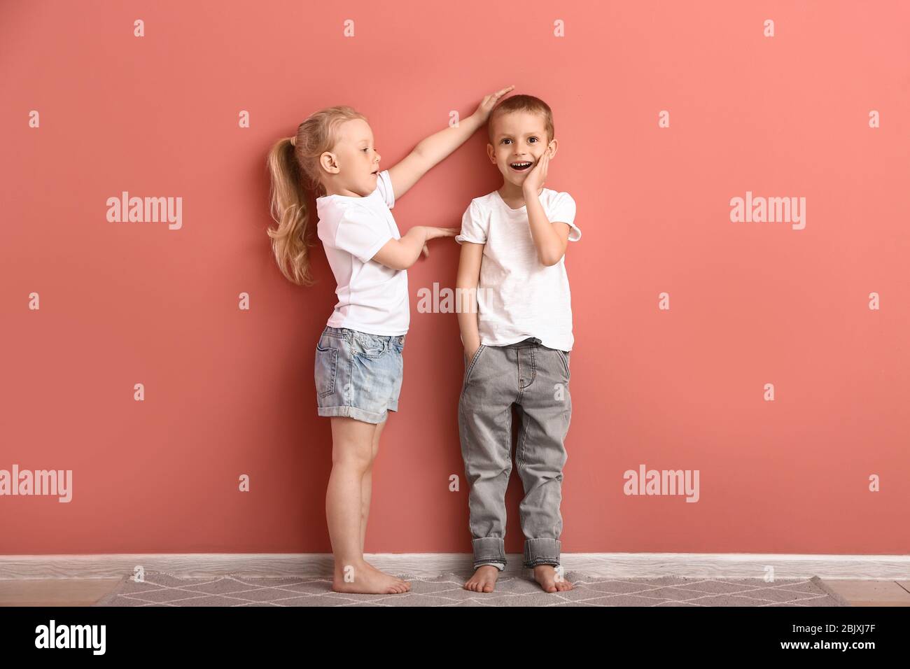 Little children measuring height near wall Stock Photo - Alamy