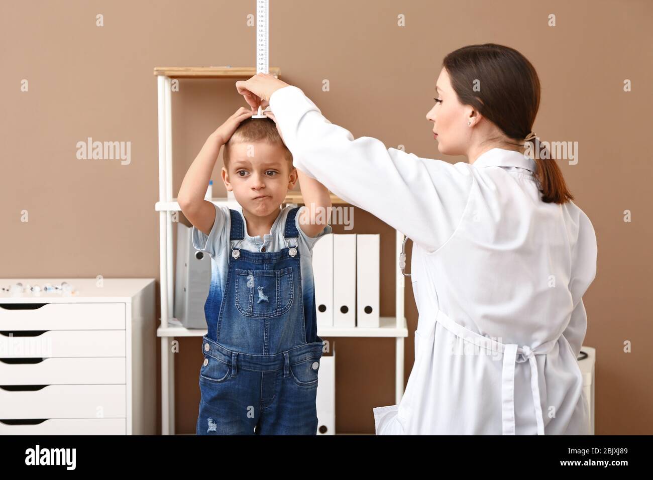 Female doctor measuring height of little boy in hospital Stock Photo ...