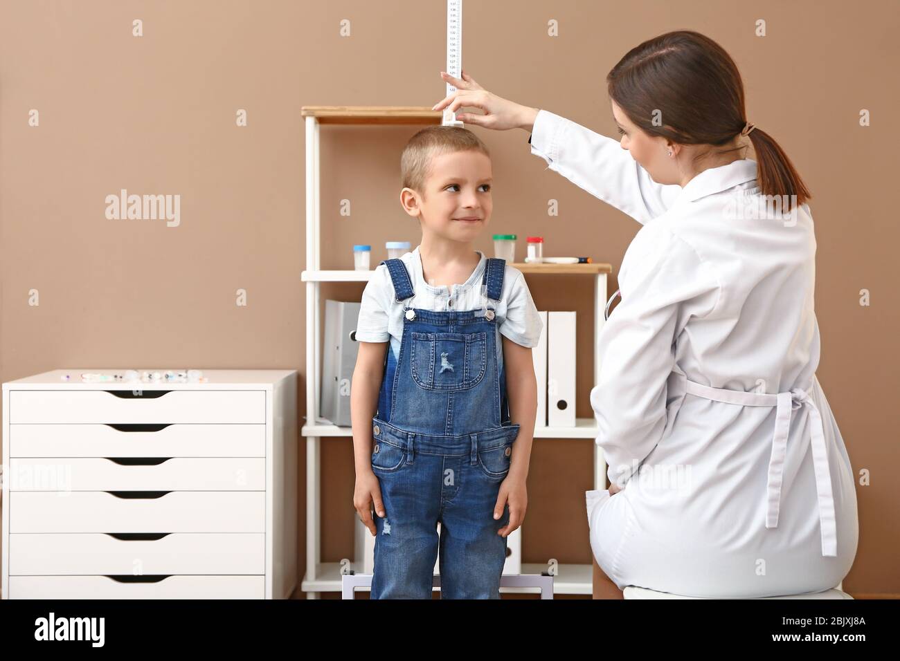 Female doctor measuring height of little boy in hospital Stock Photo ...