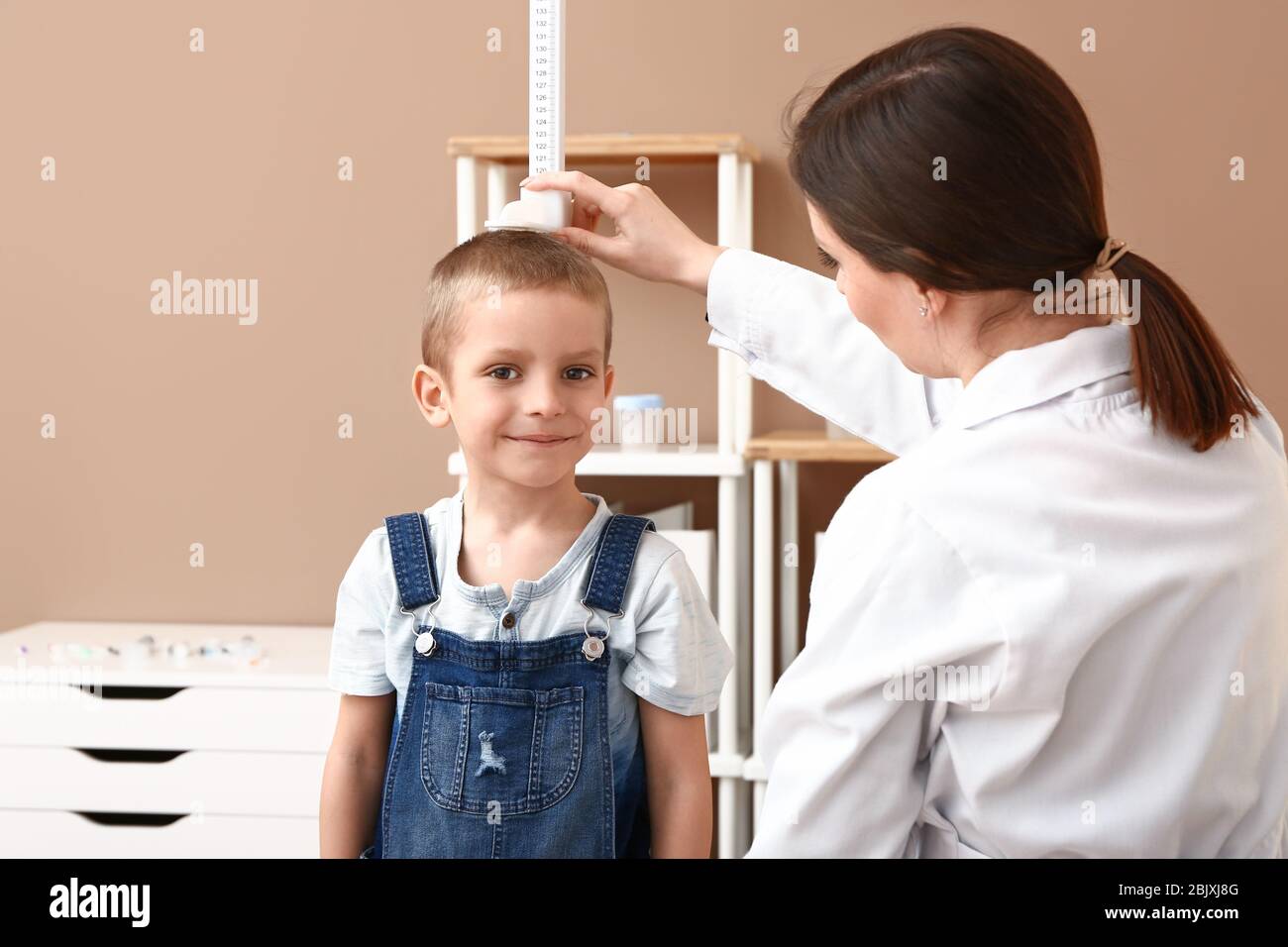 Female doctor measuring height of little boy in hospital Stock Photo ...