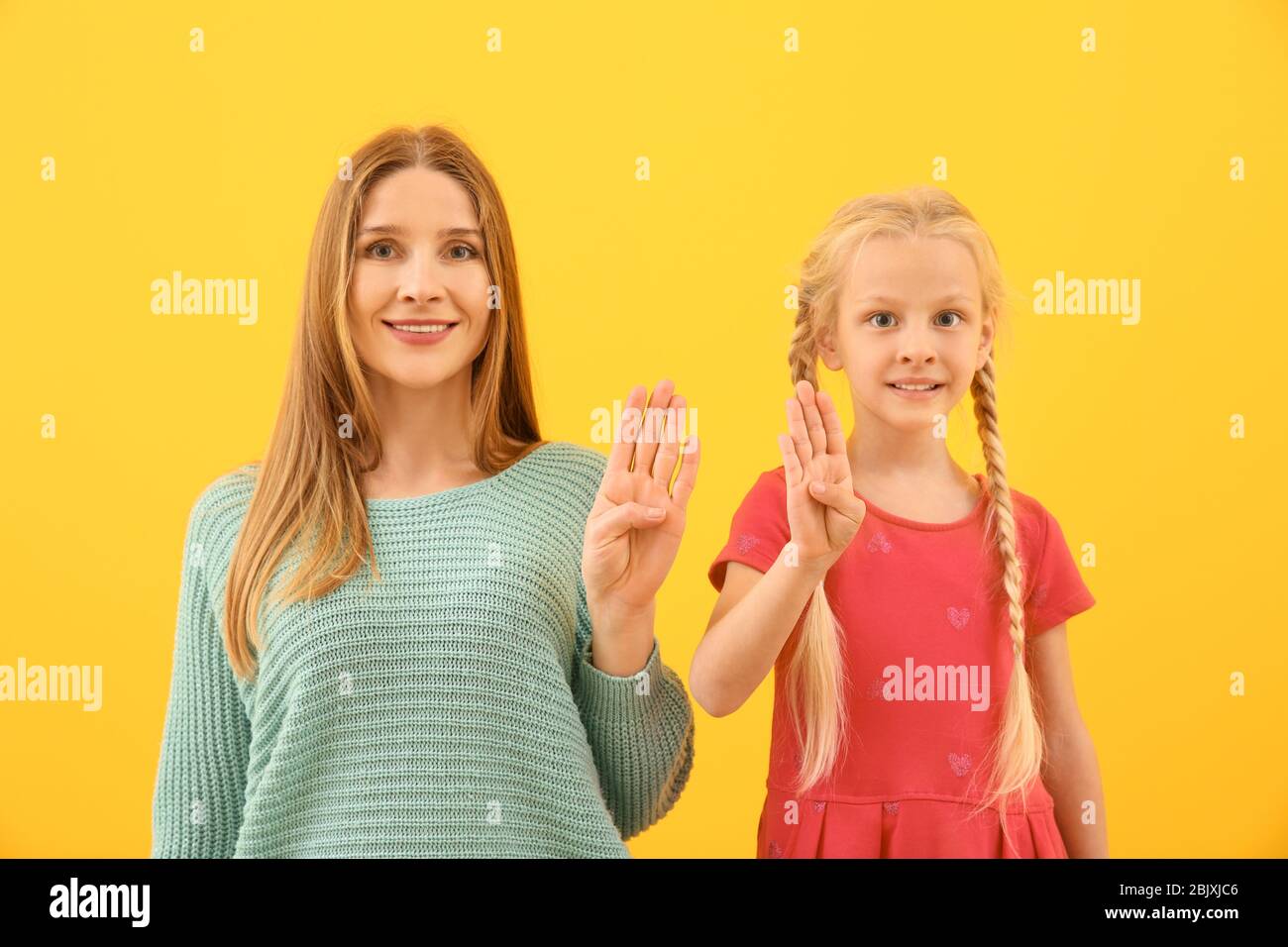 Little deaf mute girl and her mother using sign language on color ...