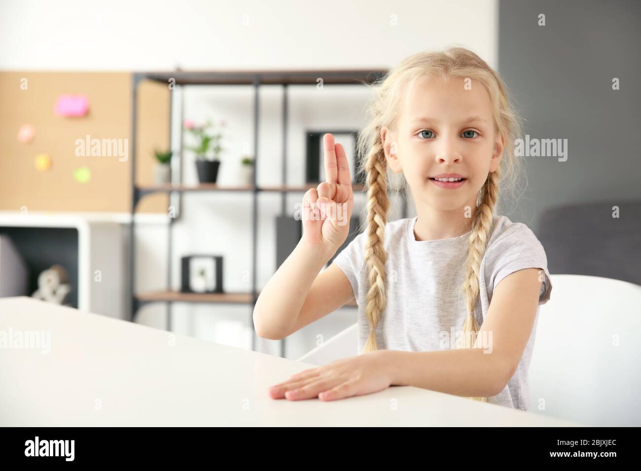 Little deaf mute girl using sign language at home Stock Photo - Alamy