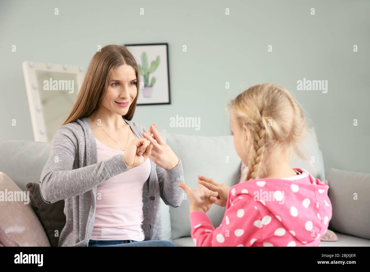 Mother teaching her deaf mute daughter to use sign language at home ...
