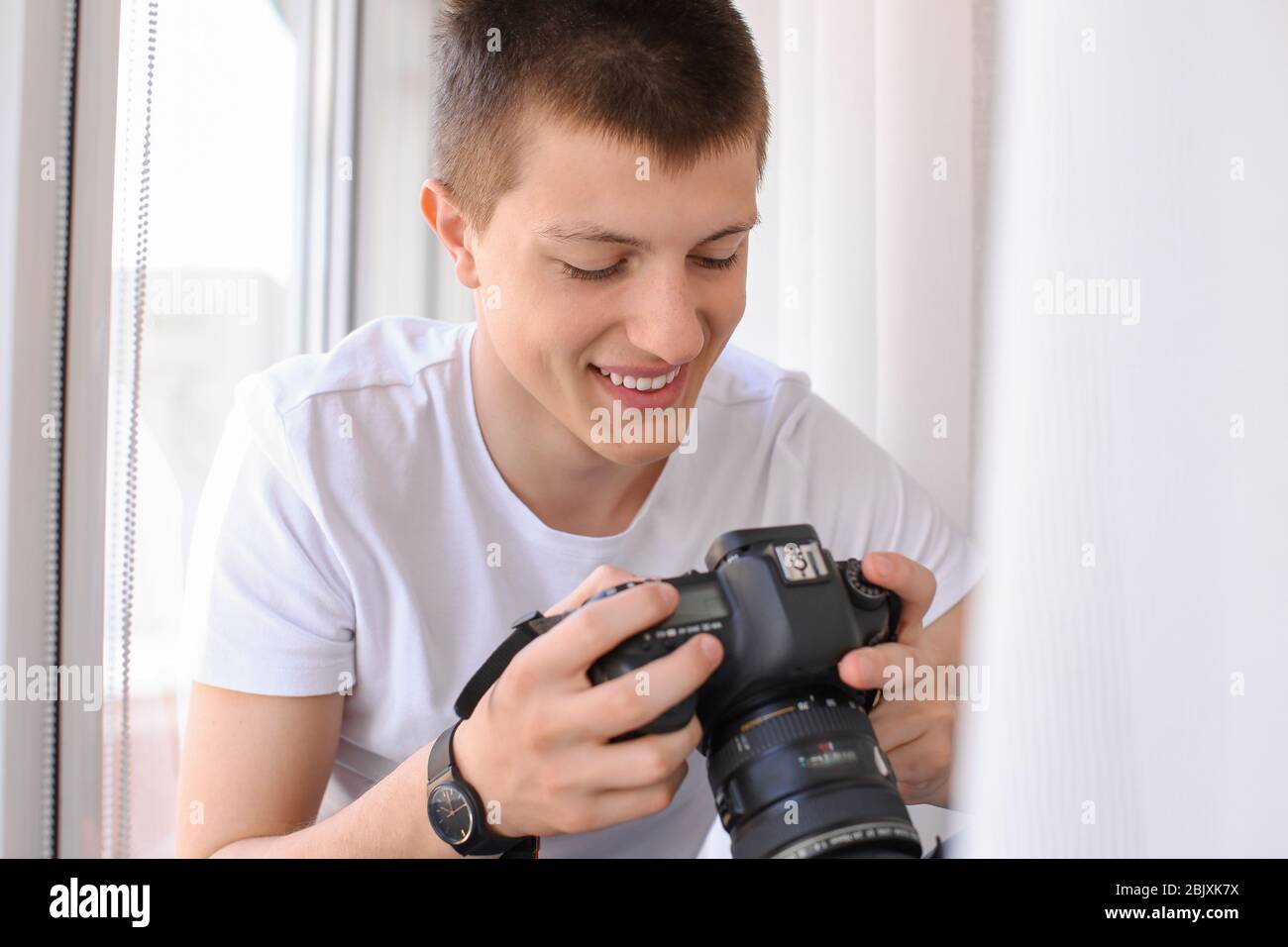 Teenage boy with photo camera near window Stock Photo - Alamy