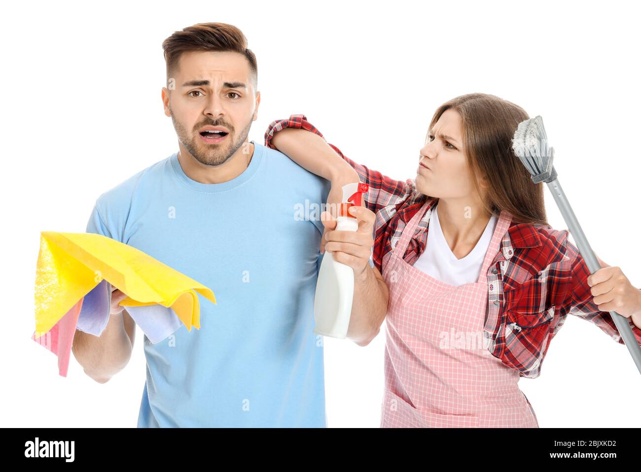Angry wife and her afraid husband with cleaning supplies on white ...
