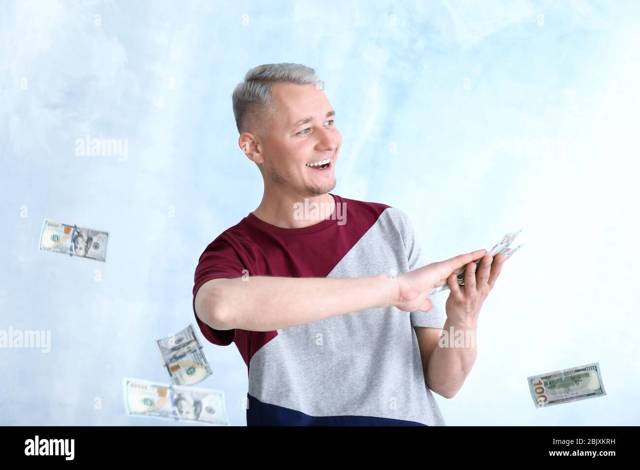 Happy young man throwing dollar banknotes on light background Stock ...