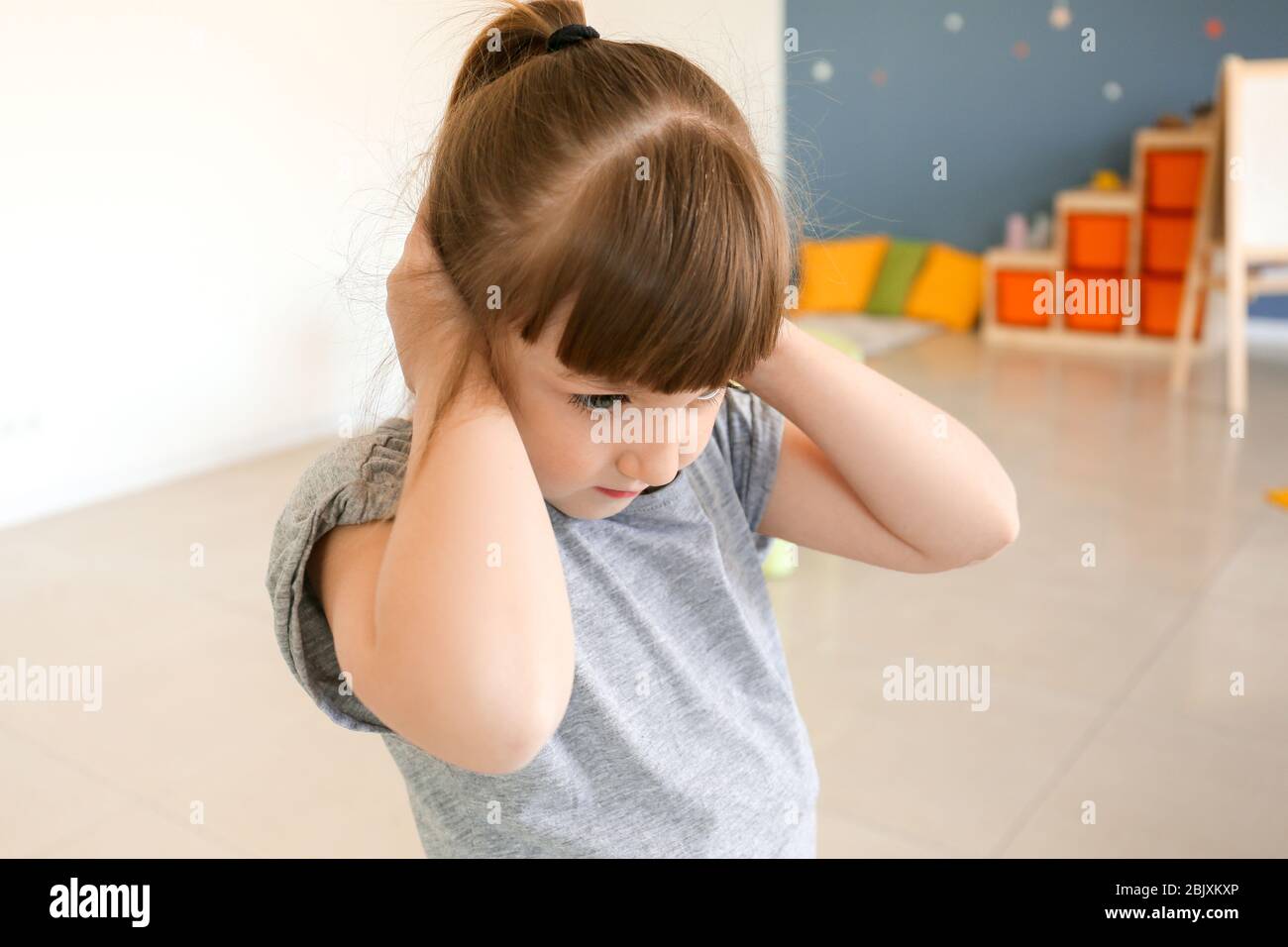 Sad little girl with autistic disorder covering ears with hands in ...