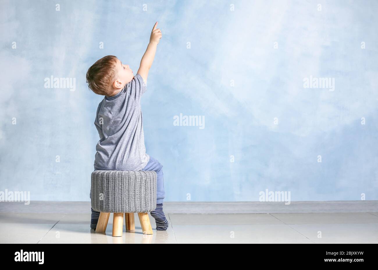 Little boy with autistic disorder sitting near light wall Stock Photo ...