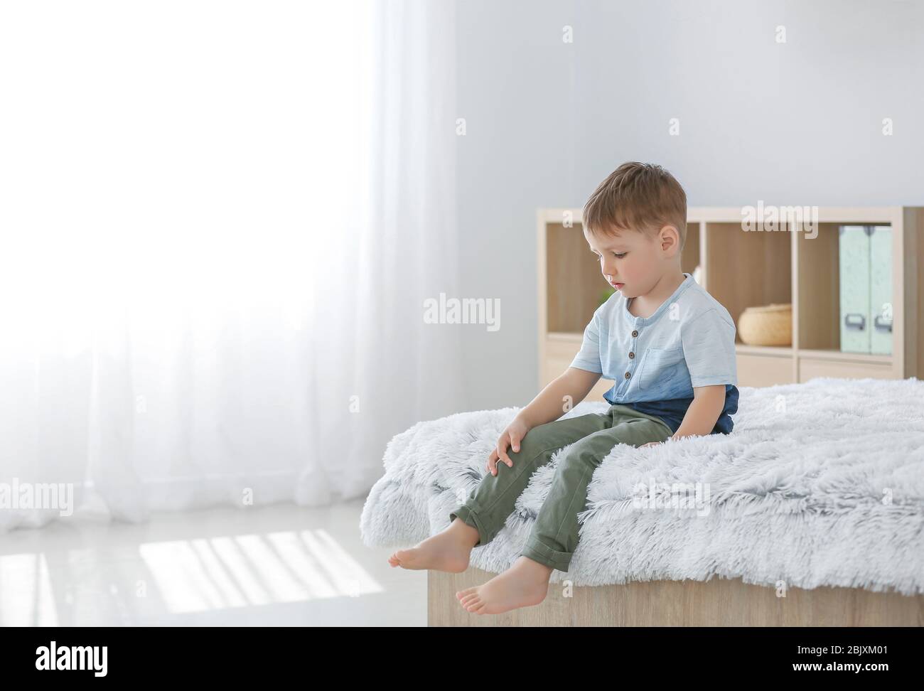 Little boy with autistic disorder sitting on bed at home Stock Photo ...