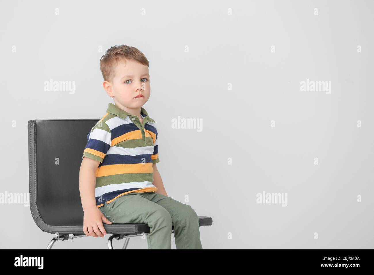 Little boy with autistic disorder sitting on chair against light ...