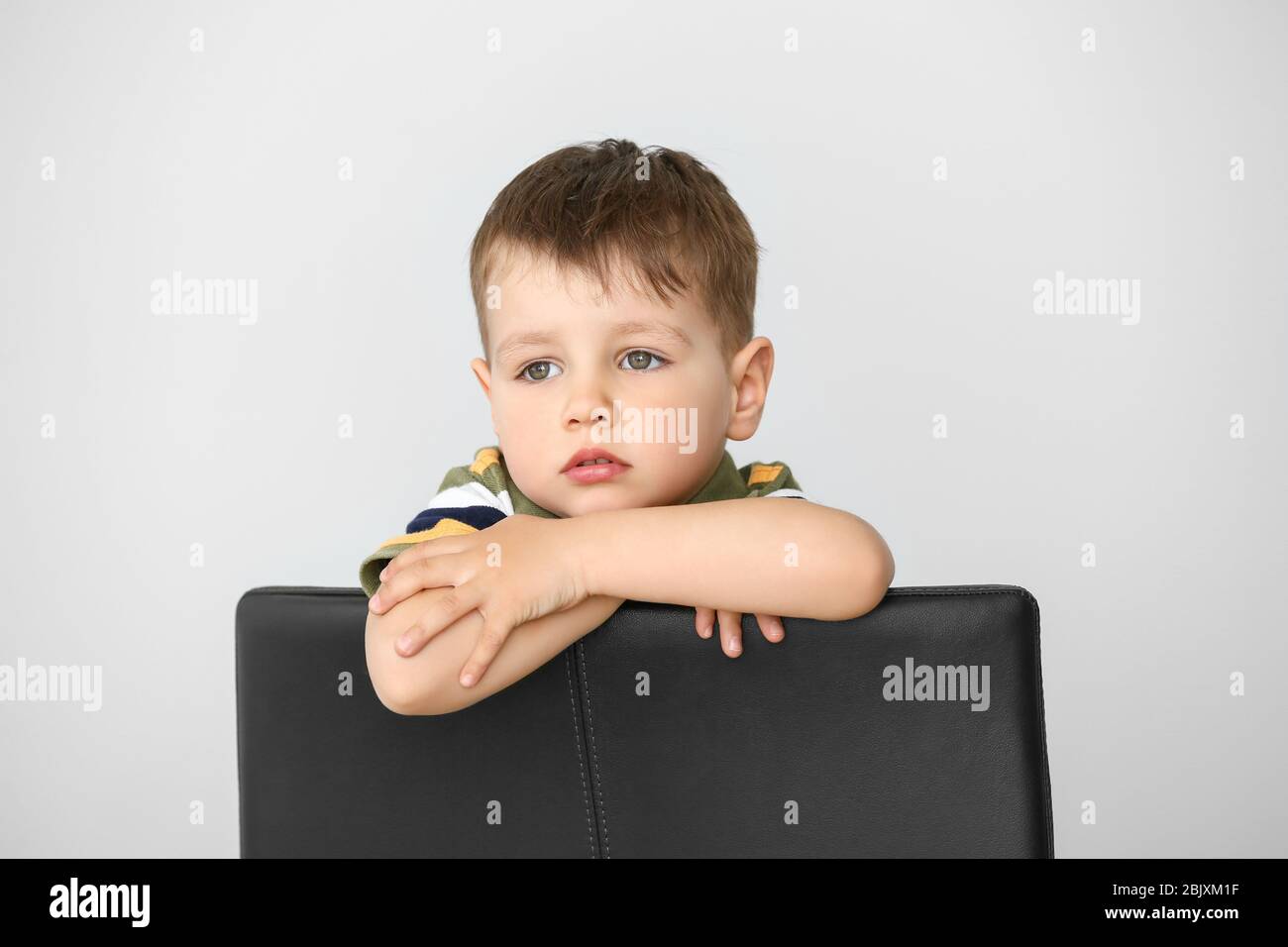 Little boy with autistic disorder sitting on chair against light ...