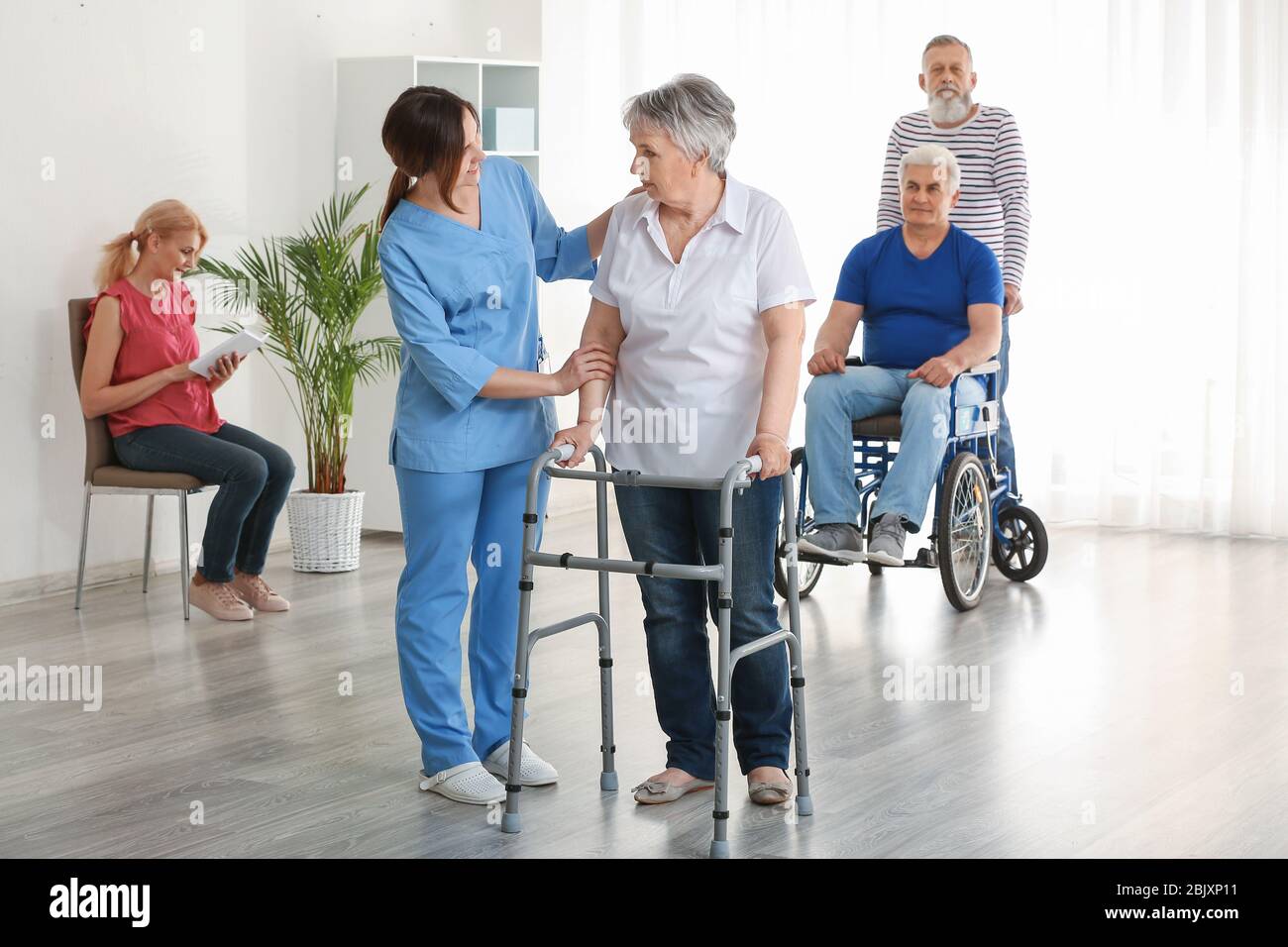 Young caregiver looking after disabled senior woman in nursing home ...