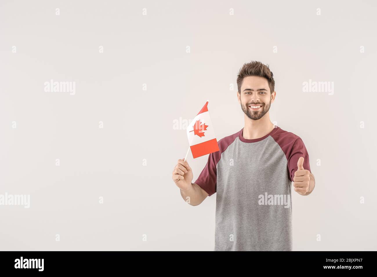 Young man with Canadian flag on light background Stock Photo - Alamy