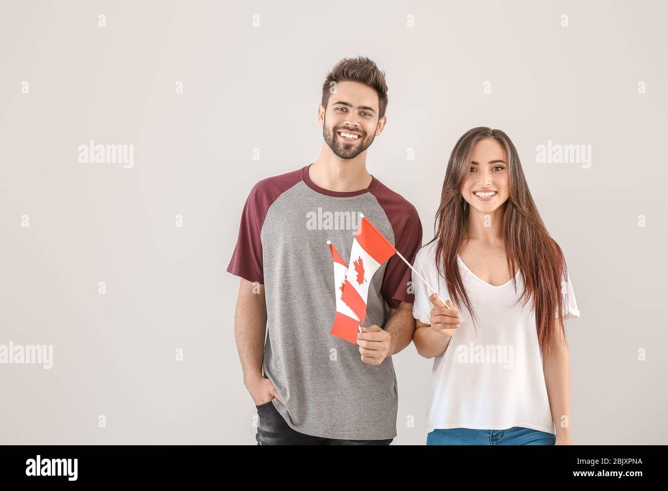 Young people with Canadian flags on light background Stock Photo - Alamy