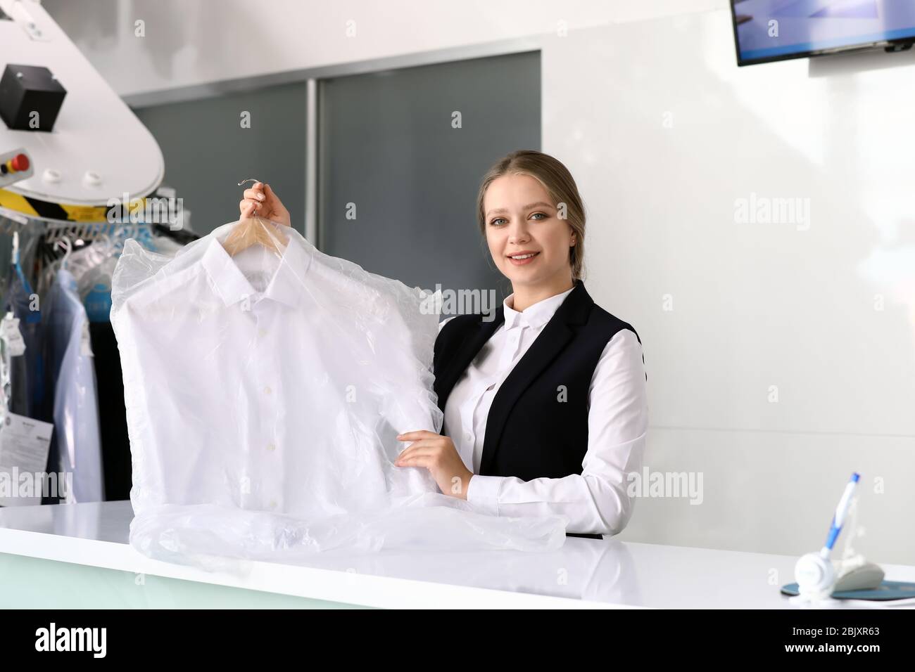 Worker of modern dry-cleaner's at reception Stock Photo - Alamy