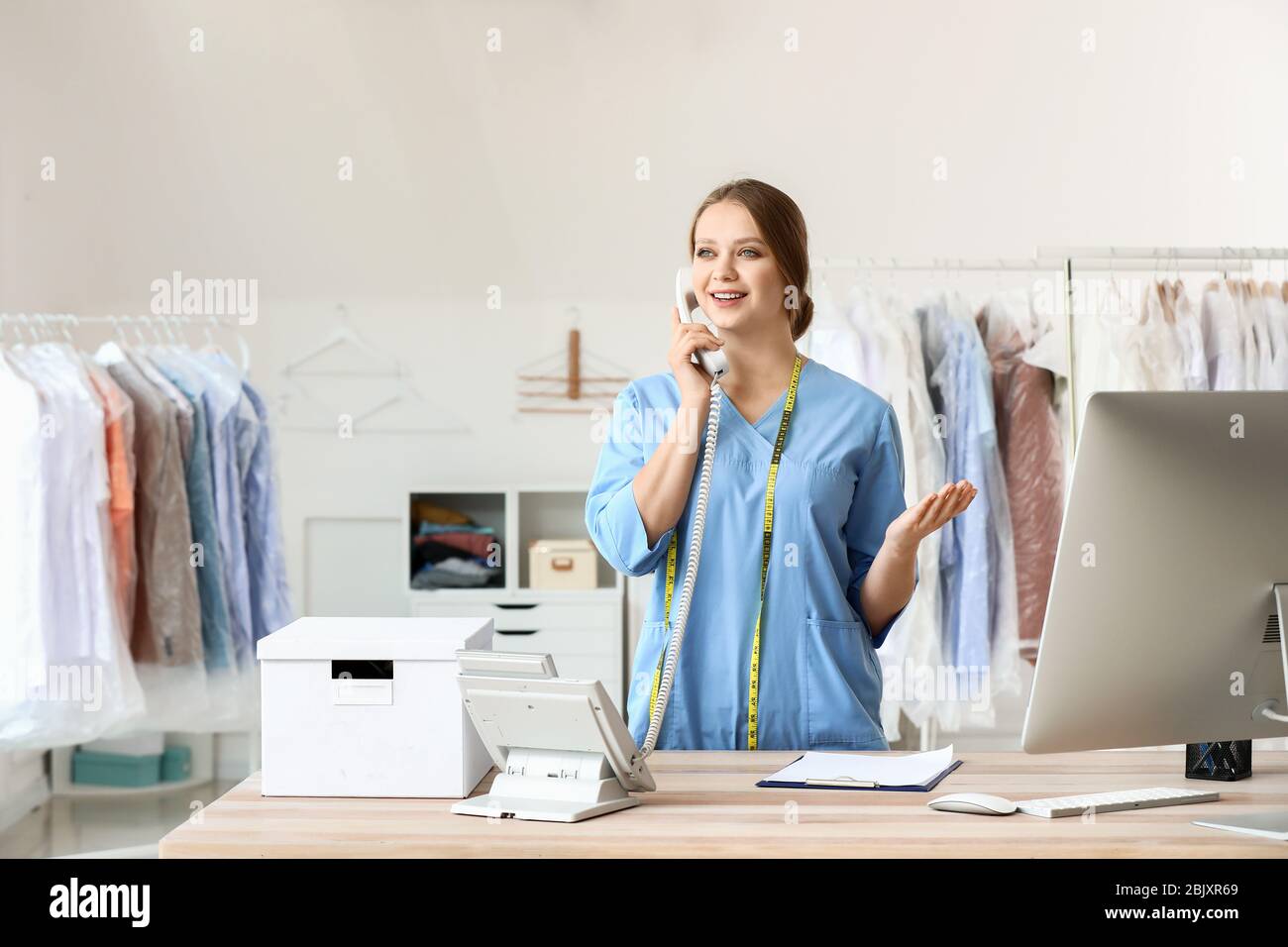 Worker of modern dry-cleaner's talking by phone at reception Stock ...