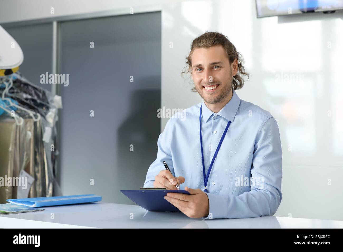 Worker of modern dry-cleaner's at reception Stock Photo - Alamy