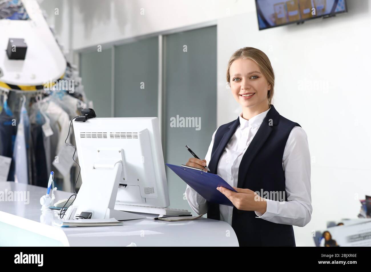 Worker of modern dry-cleaner's at reception Stock Photo - Alamy