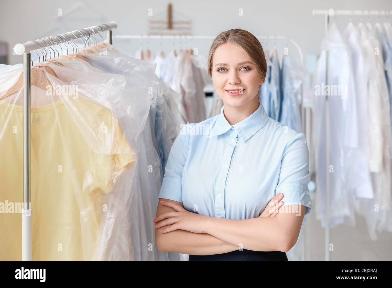 Worker of modern dry-cleaner's near rack with clothes Stock Photo - Alamy