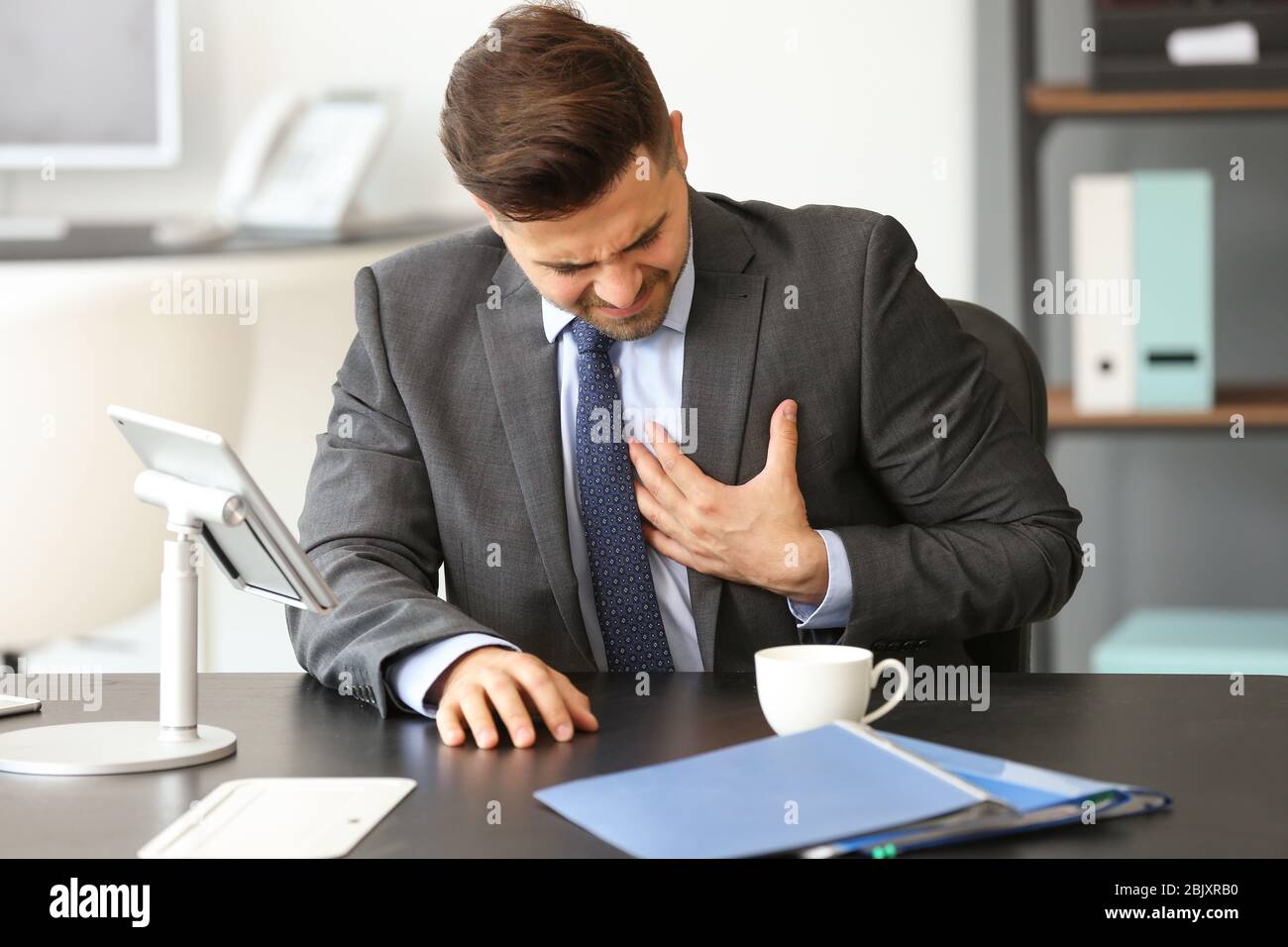 Young businessman having heart attack in office Stock Photo - Alamy