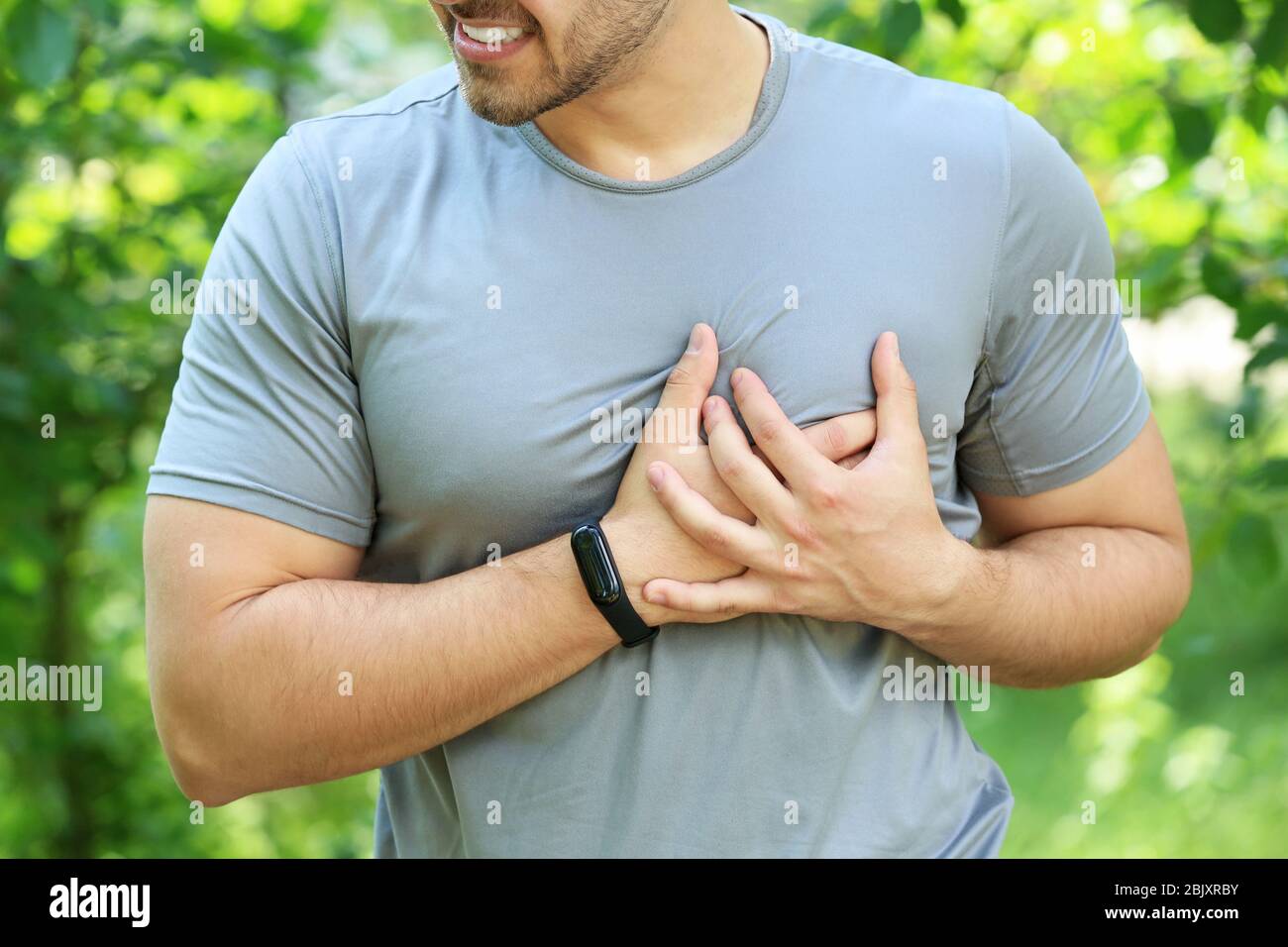 Sporty young man suffering from heart attack outdoors Stock Photo - Alamy