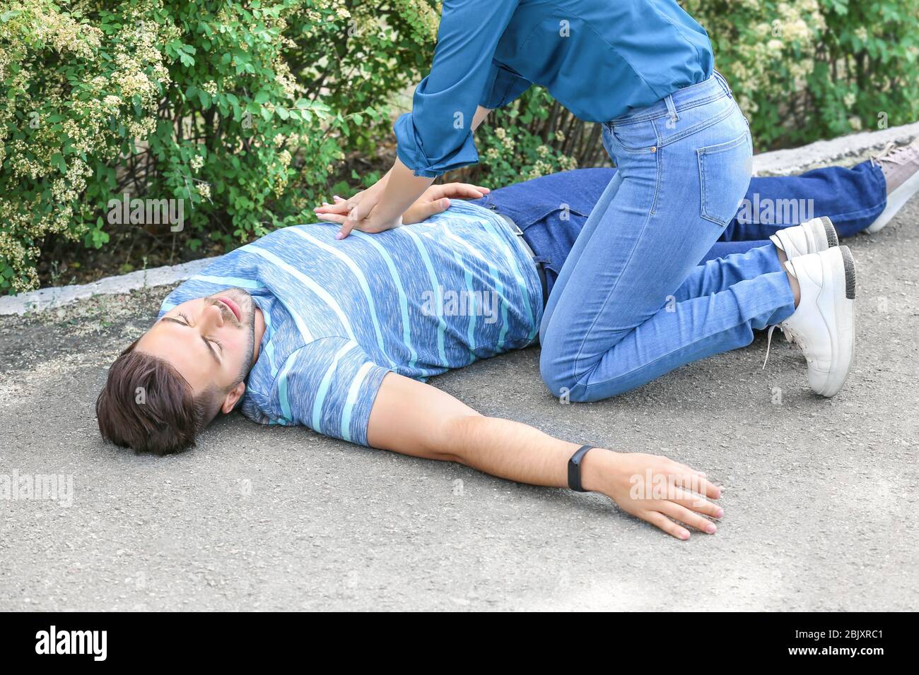 Woman giving CPR to unconscious man outdoors Stock Photo - Alamy
