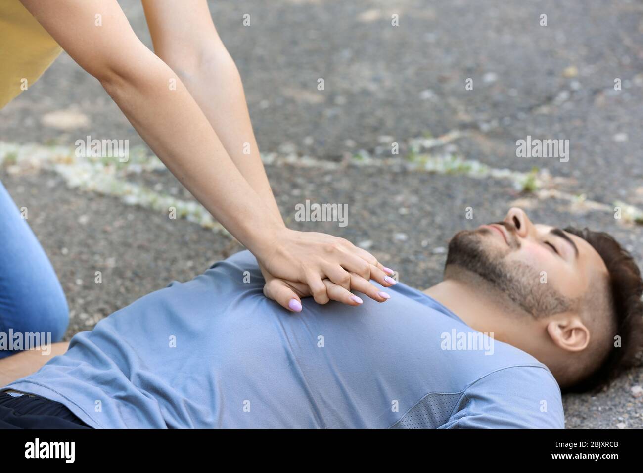 Woman giving CPR to unconscious man outdoors Stock Photo - Alamy