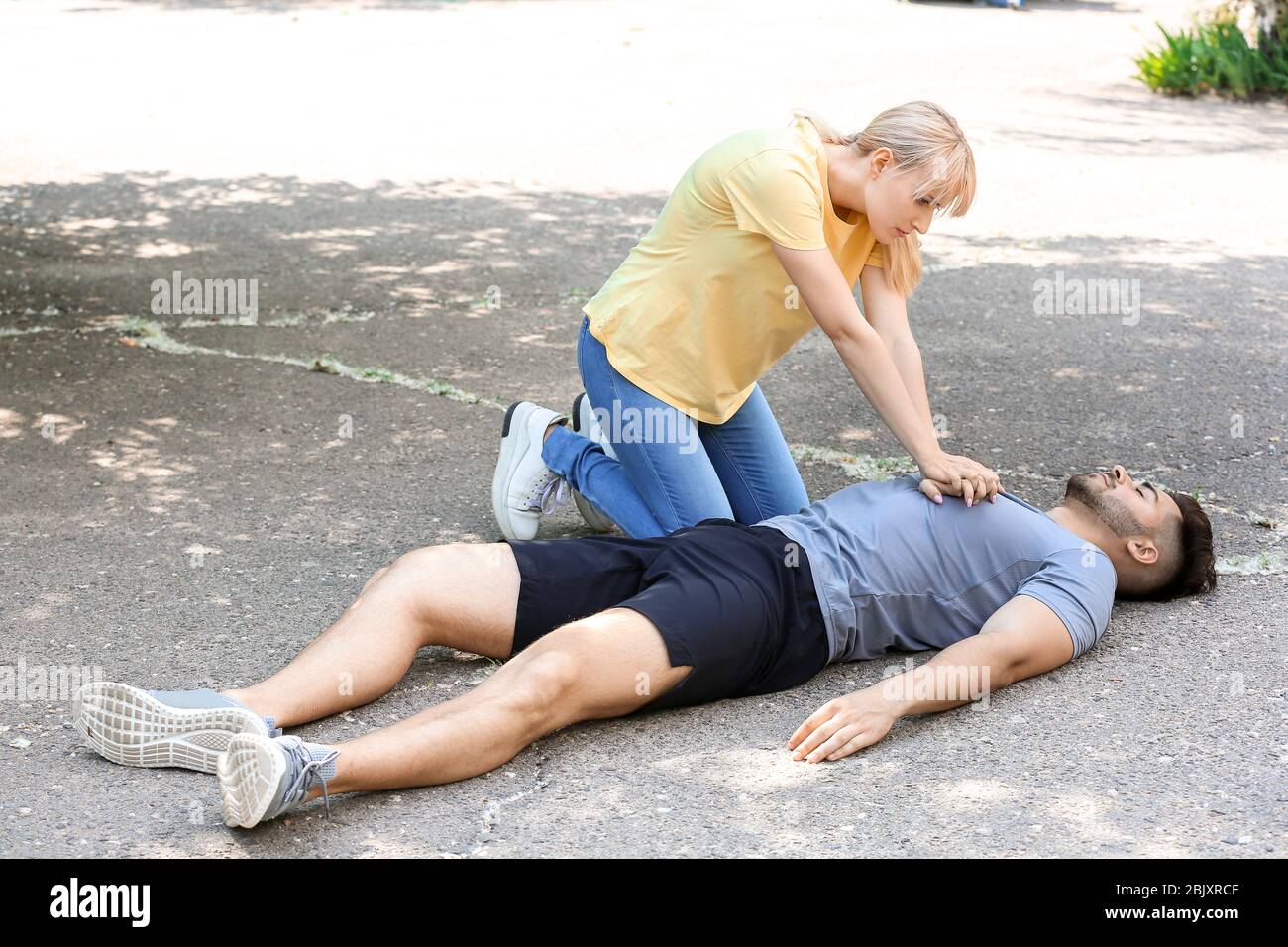 Woman giving CPR to unconscious man outdoors Stock Photo - Alamy