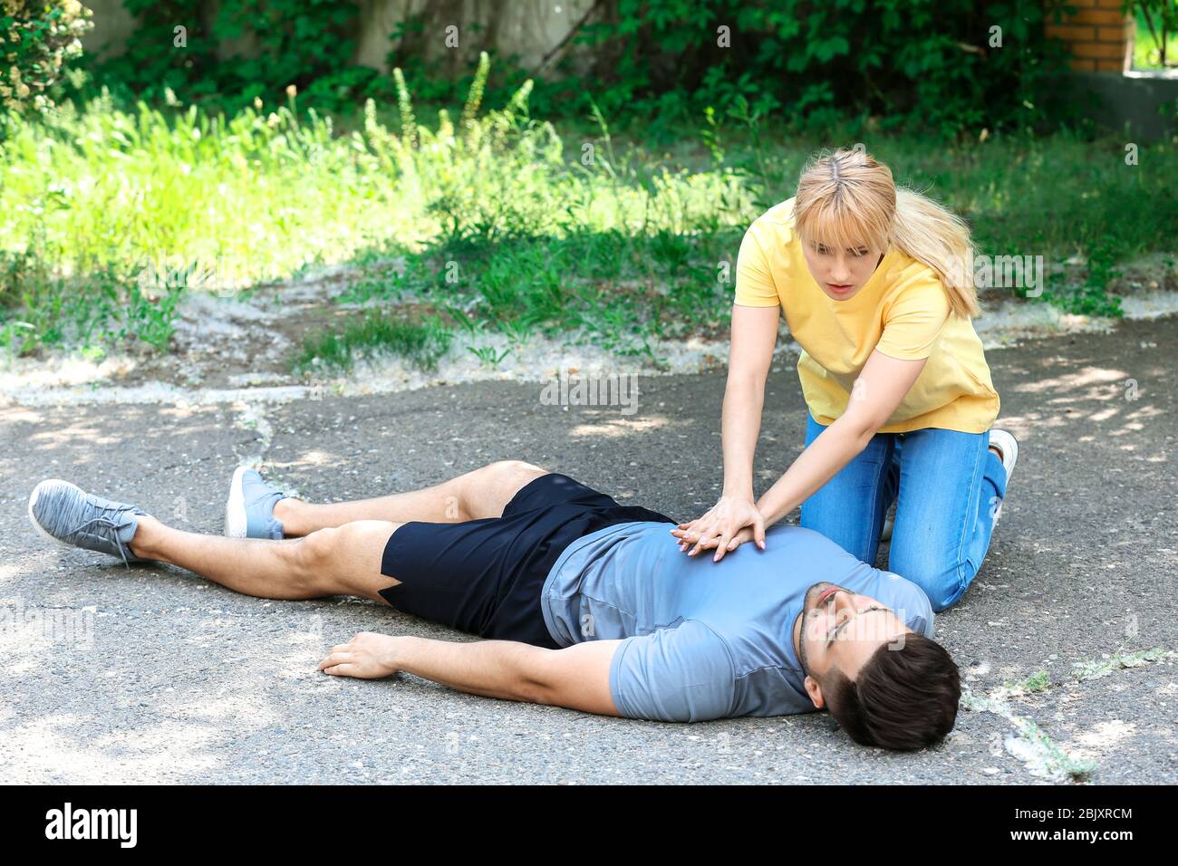 Woman giving CPR to unconscious man outdoors Stock Photo - Alamy
