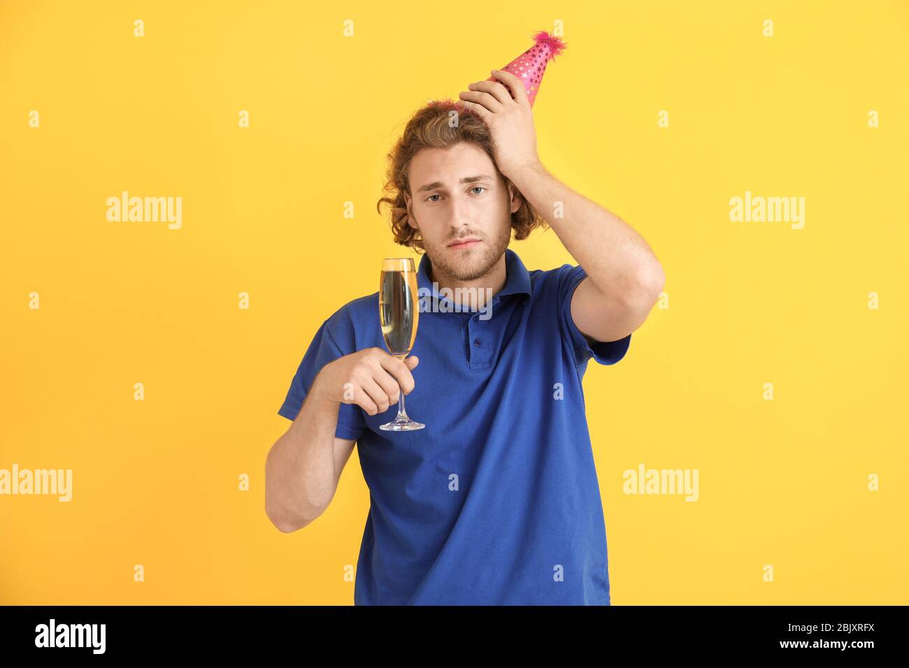 Drunk man with party hat and glass of champagne on color background ...