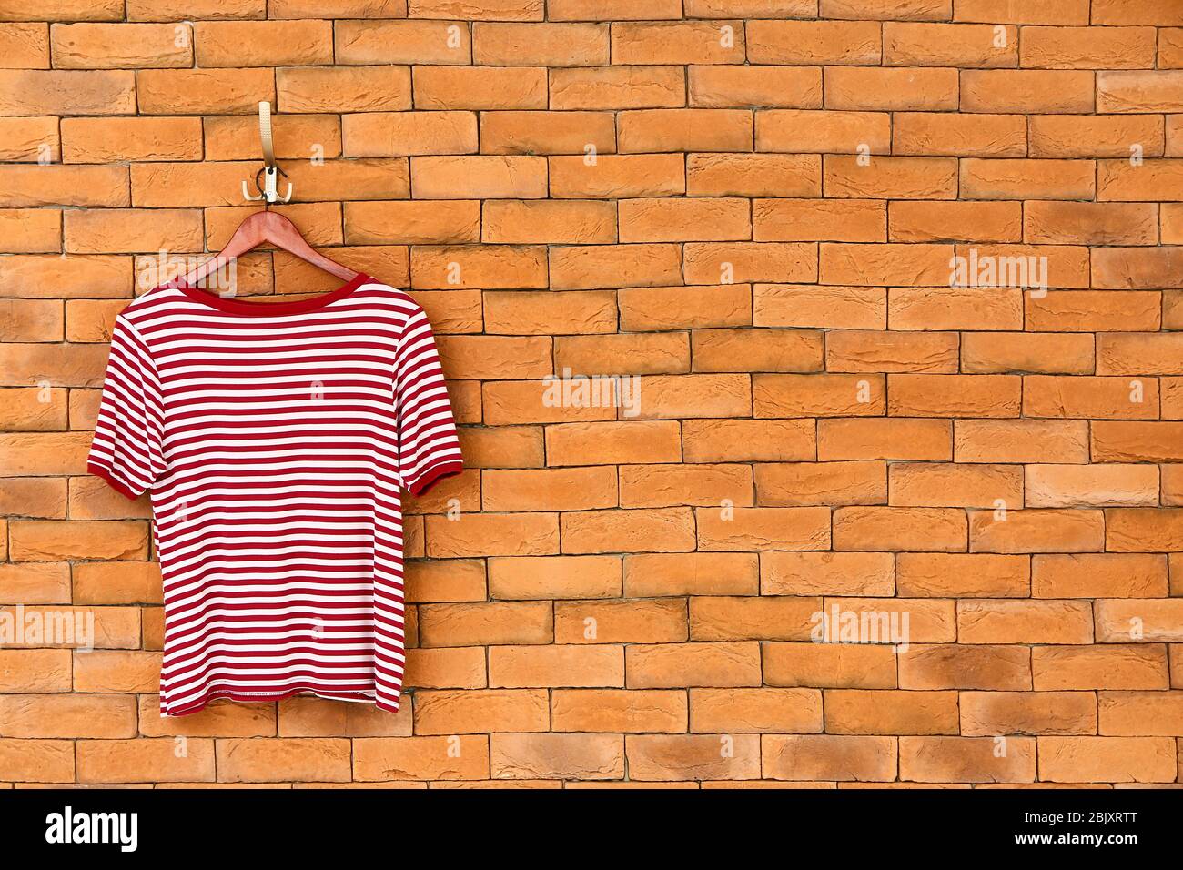 Hanger with clothes on brick wall Stock Photo - Alamy